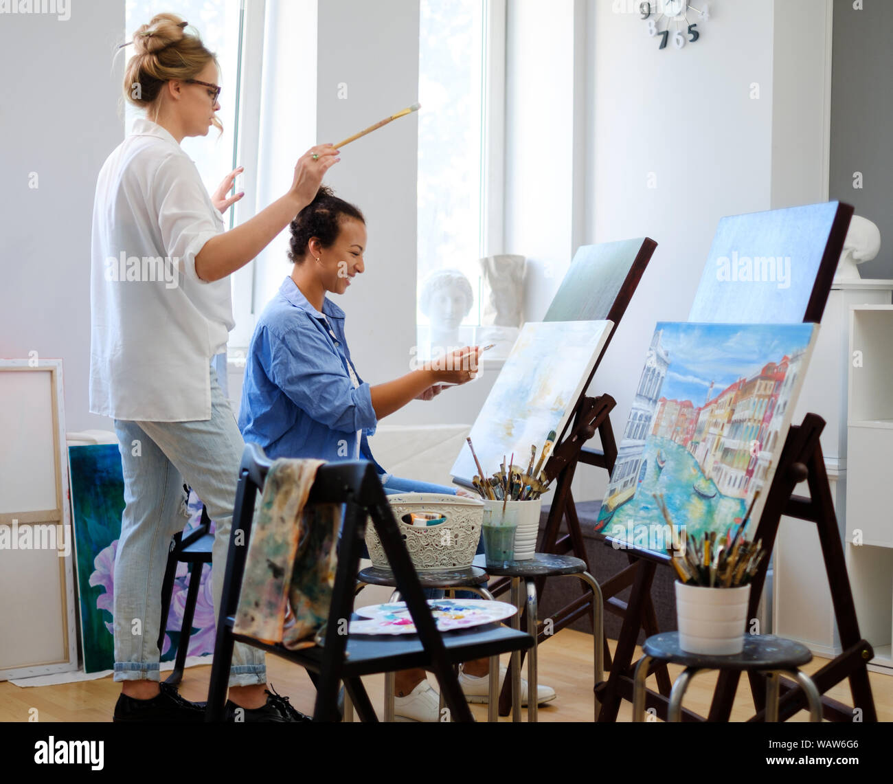 Creative painter and her protege working in a studio Stock Photo - Alamy