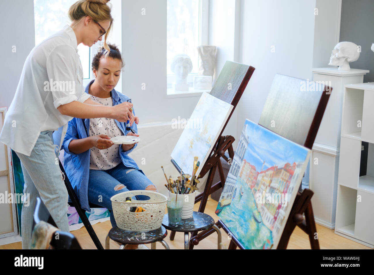 Creative painter and her protege working in a studio Stock Photo - Alamy