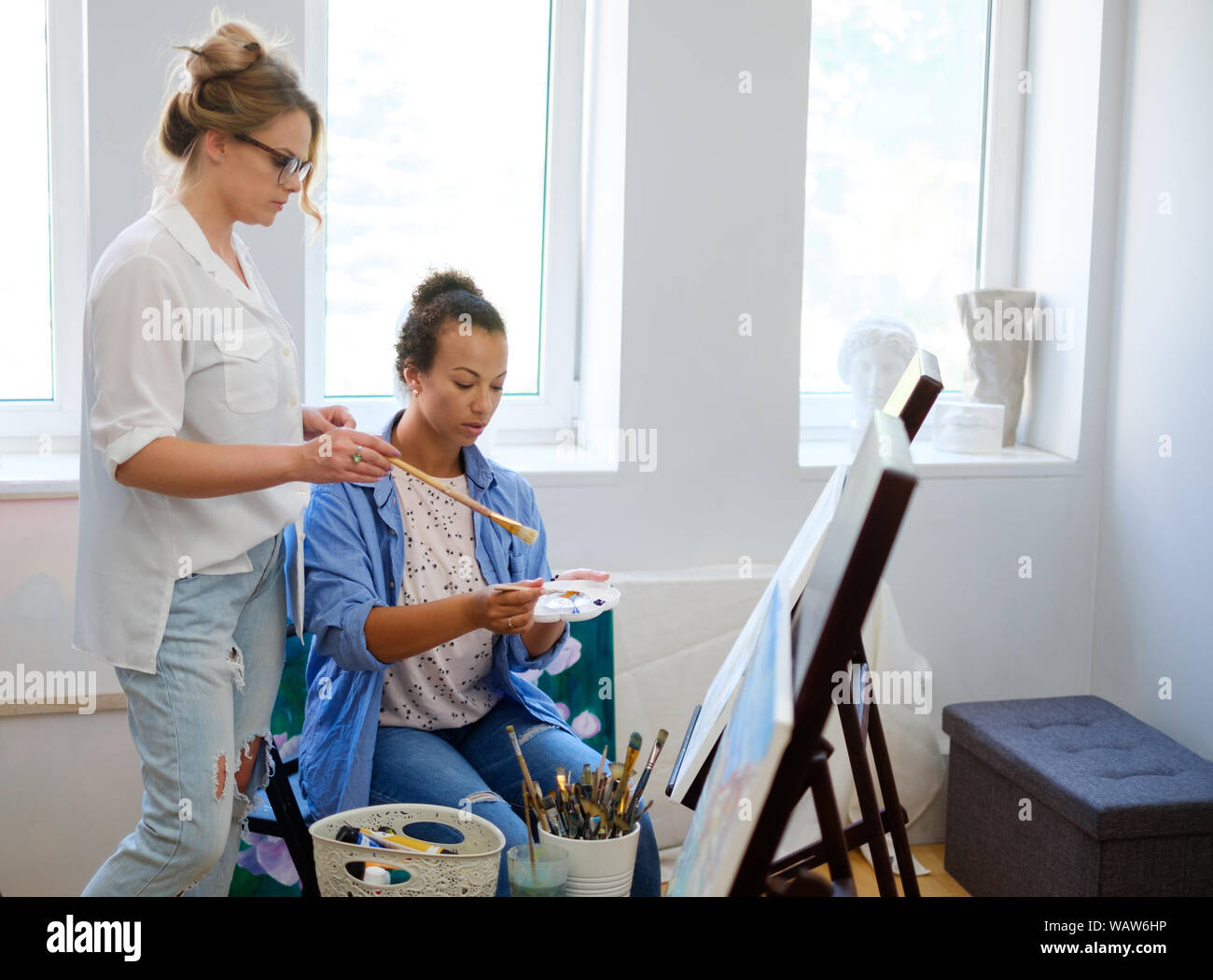Creative painter and her protege working in a studio Stock Photo - Alamy