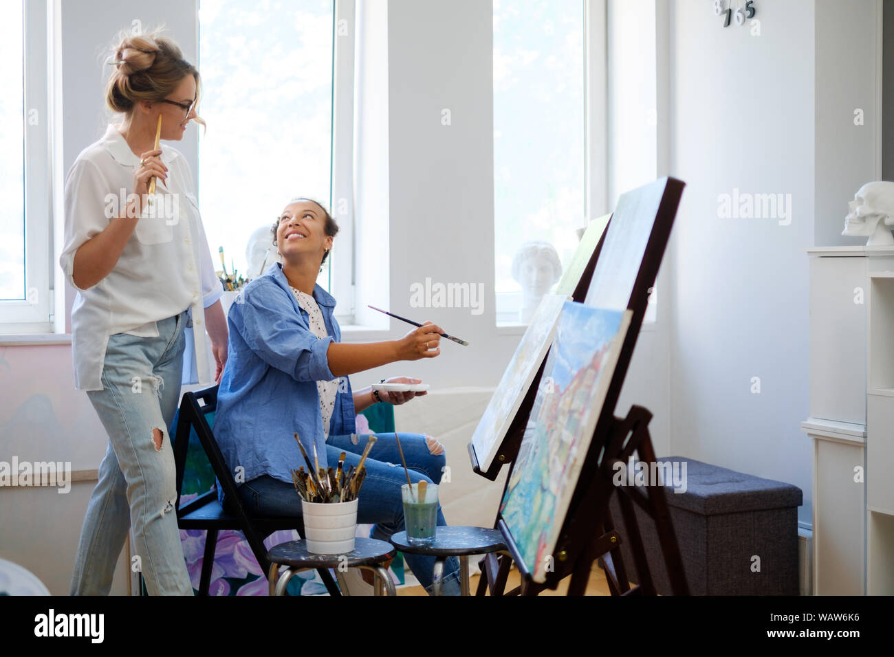 Creative painter and her protege working in a studio Stock Photo - Alamy