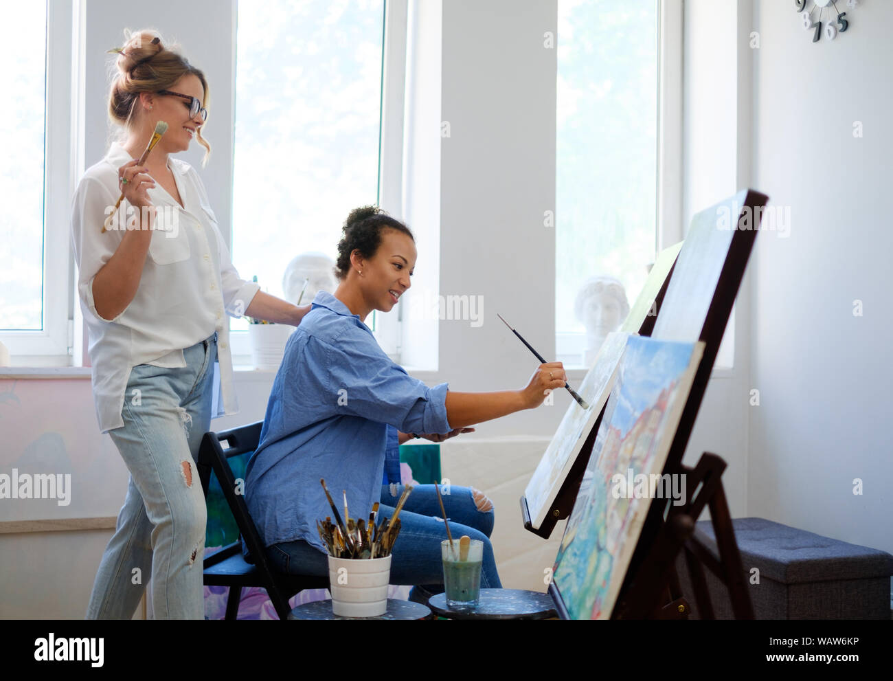 Creative painter and her protege working in a studio Stock Photo - Alamy