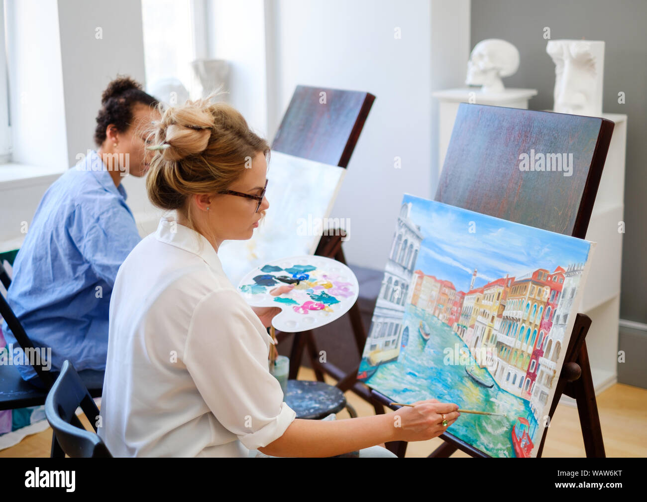 Creative painter and her protege working in a studio Stock Photo - Alamy