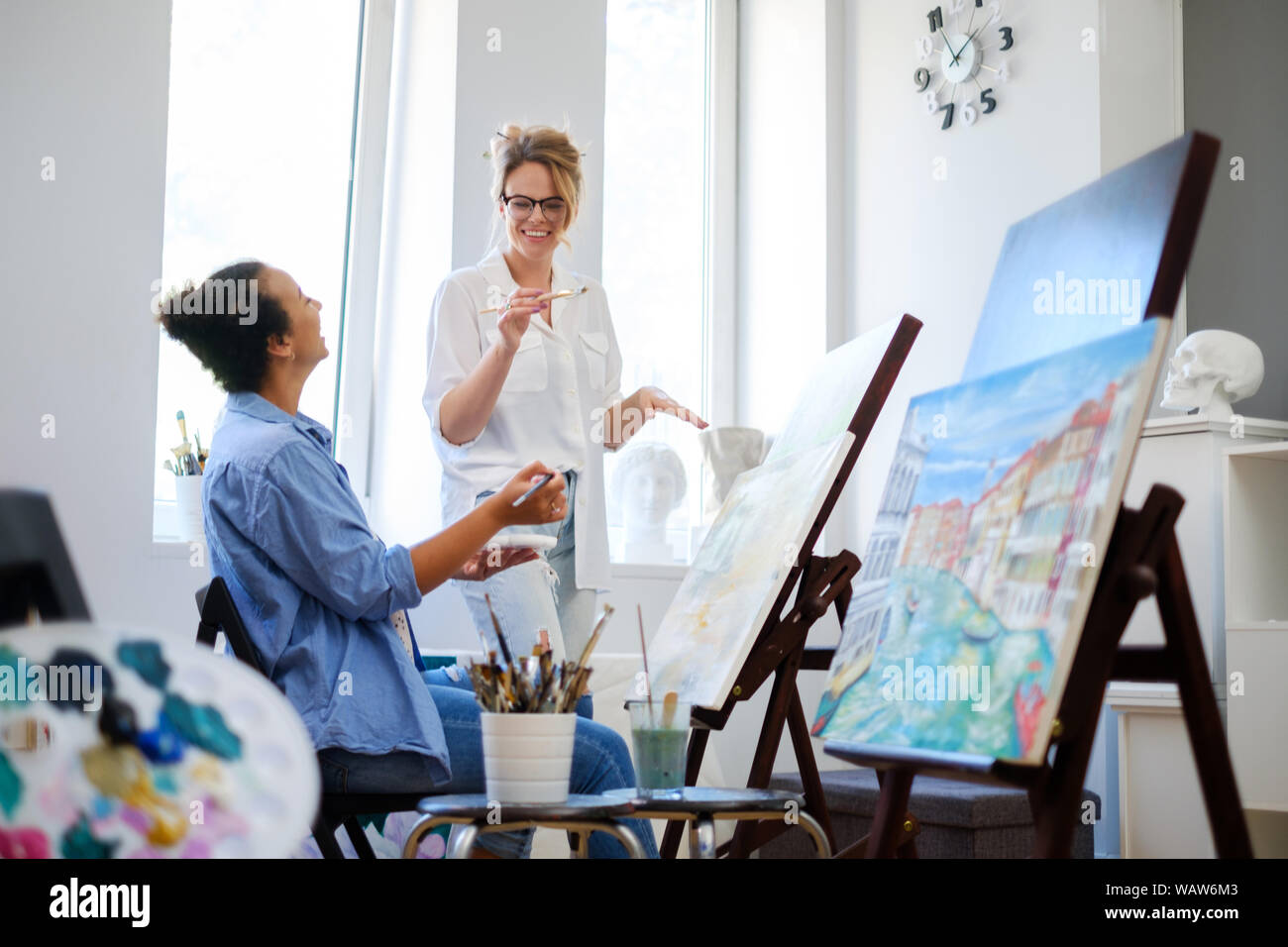 Creative painter and her protege working in a studio Stock Photo - Alamy