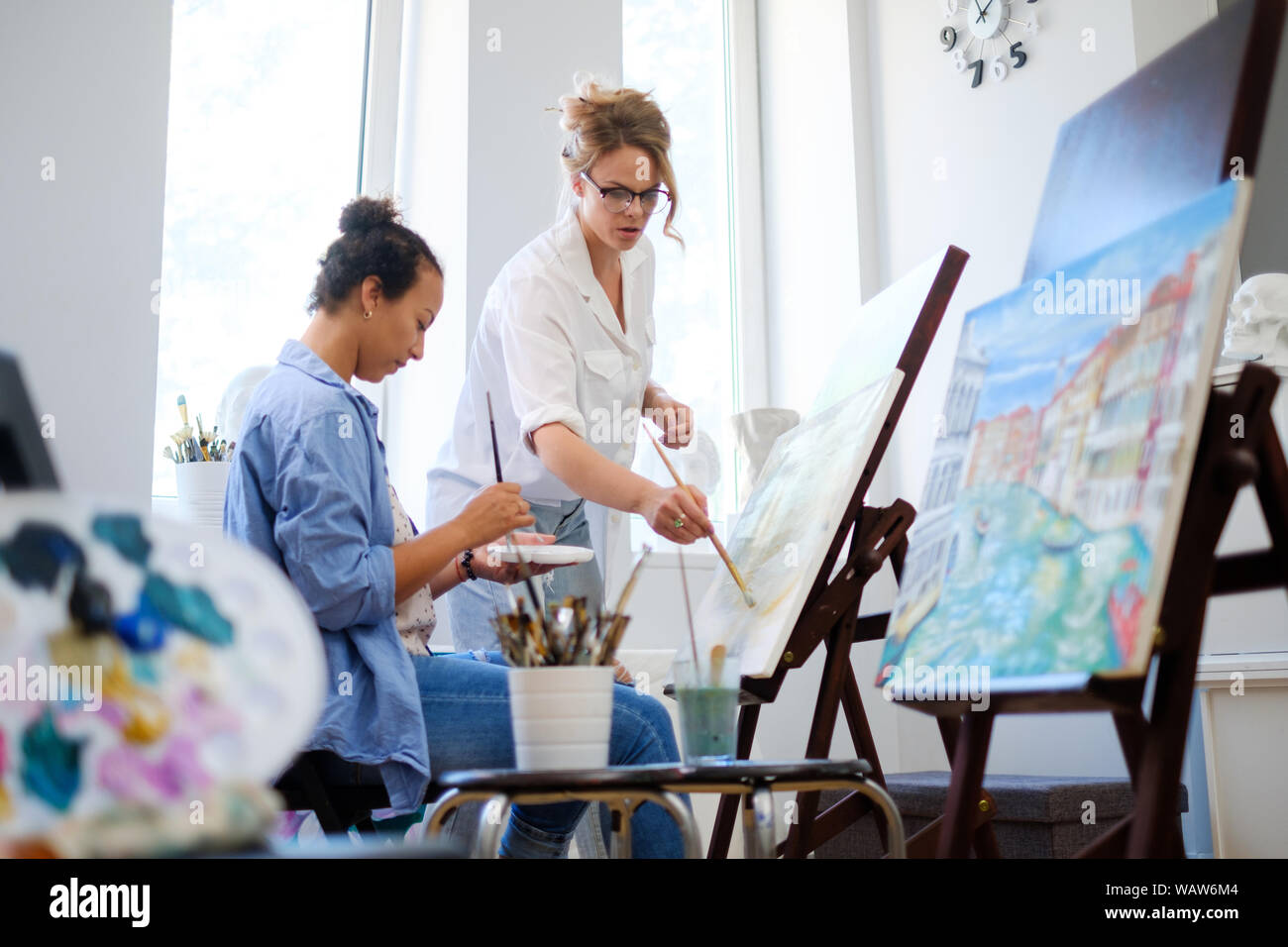 Creative painter and her protege working in a studio Stock Photo - Alamy