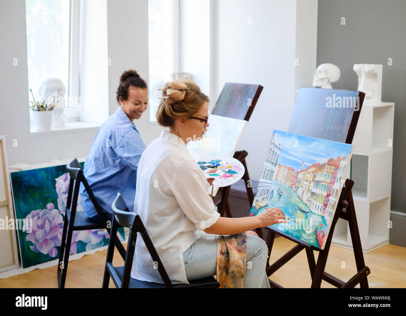 Creative painter and her protege working in a studio Stock Photo - Alamy
