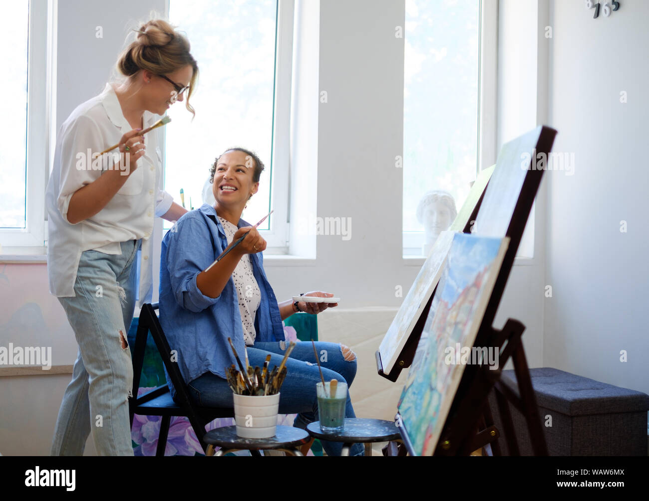 Creative painter and her protege working in a studio Stock Photo - Alamy