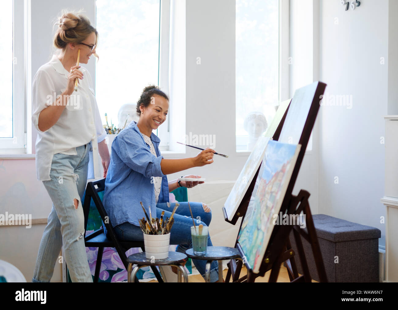 Creative painter and her protege working in a studio Stock Photo - Alamy