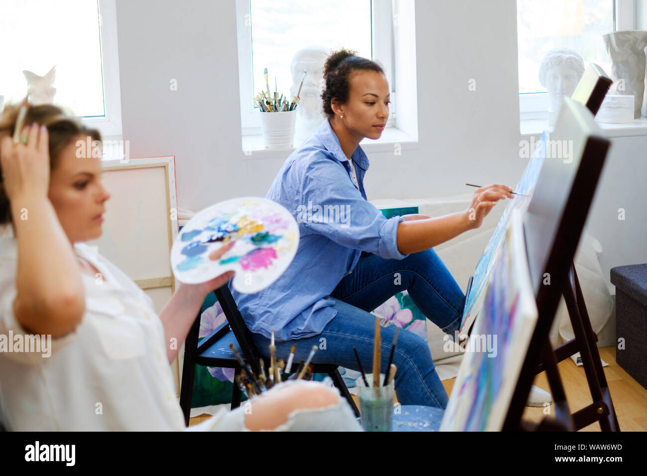 Creative painter and her protege working in a studio Stock Photo - Alamy