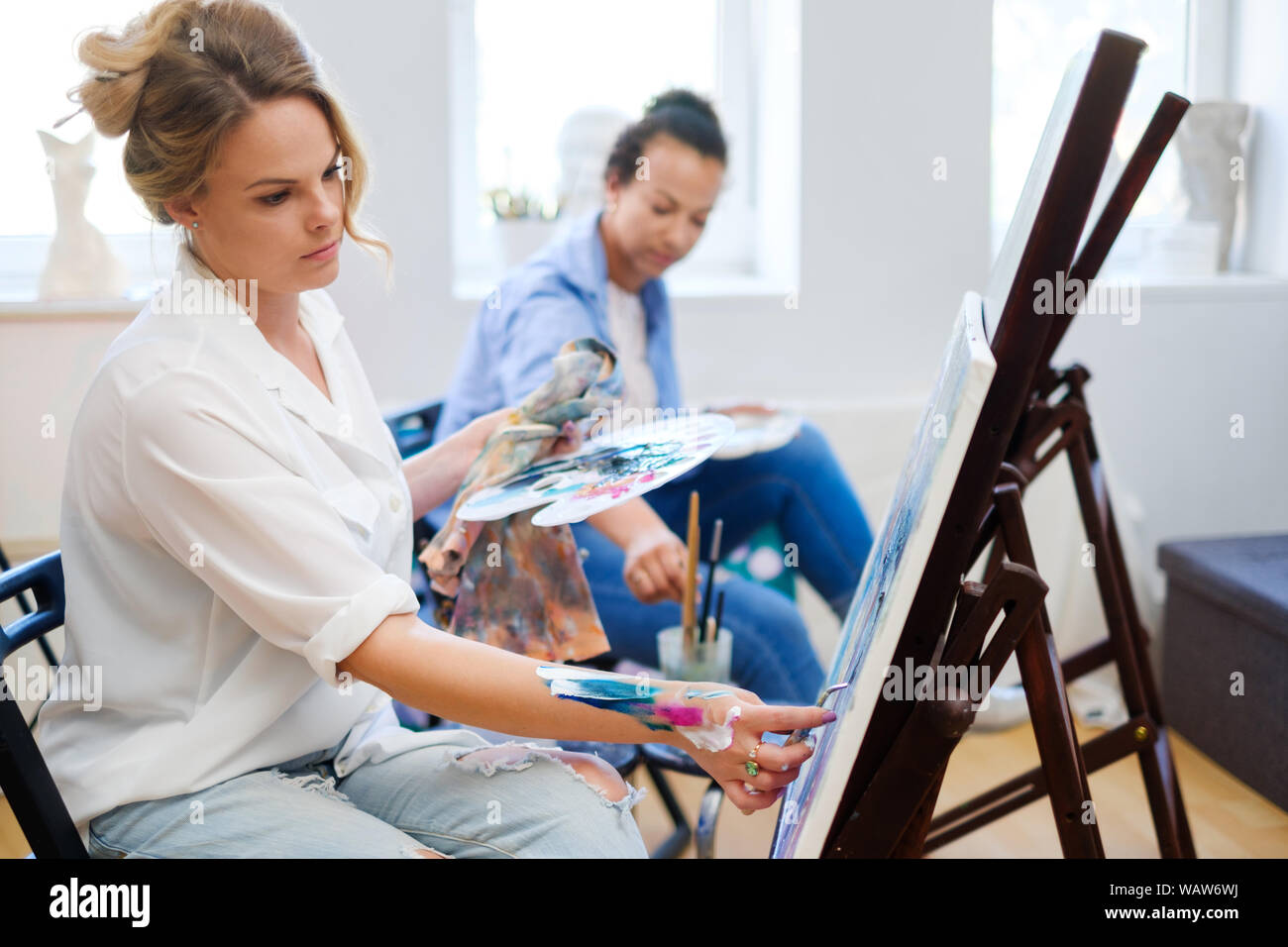 Creative painter and her protege working in a studio Stock Photo - Alamy