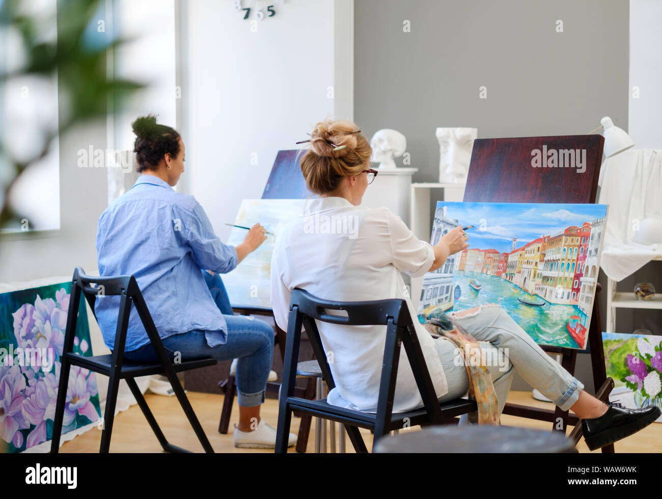 Creative painter and her protege working in a studio Stock Photo - Alamy