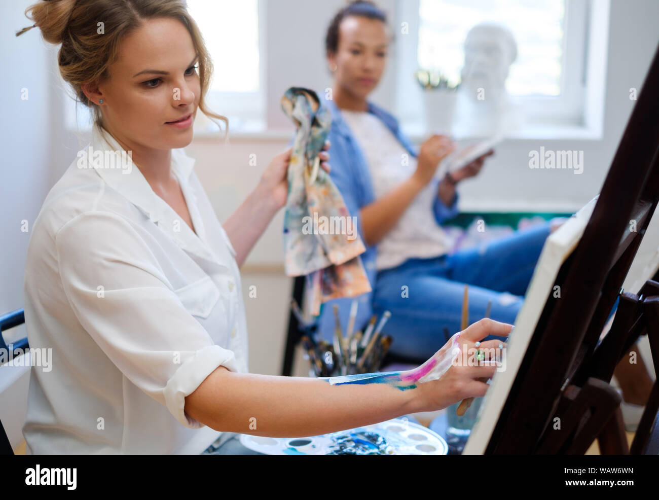 Creative painter and her protege working in a studio Stock Photo - Alamy