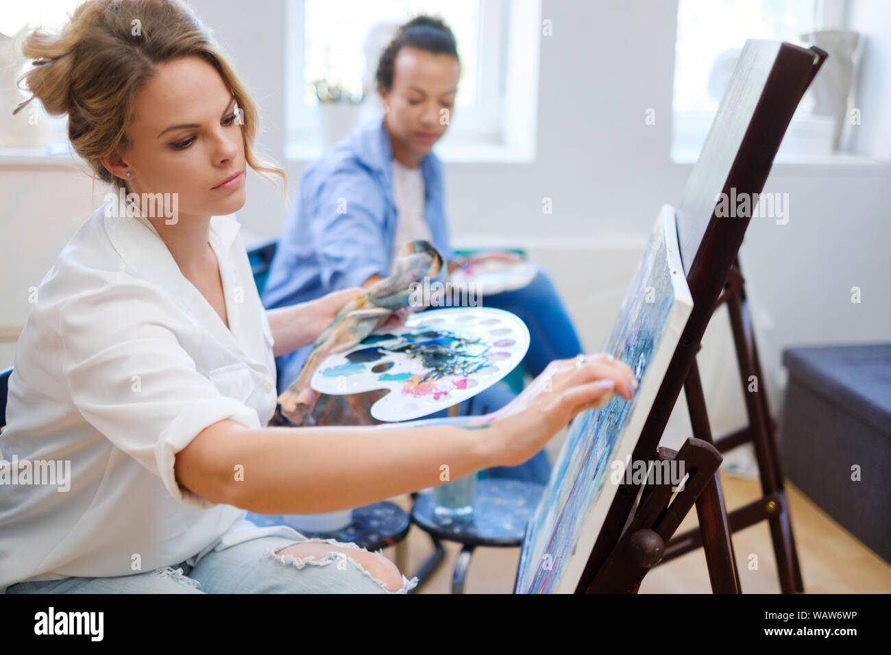Creative painter and her protege working in a studio Stock Photo - Alamy