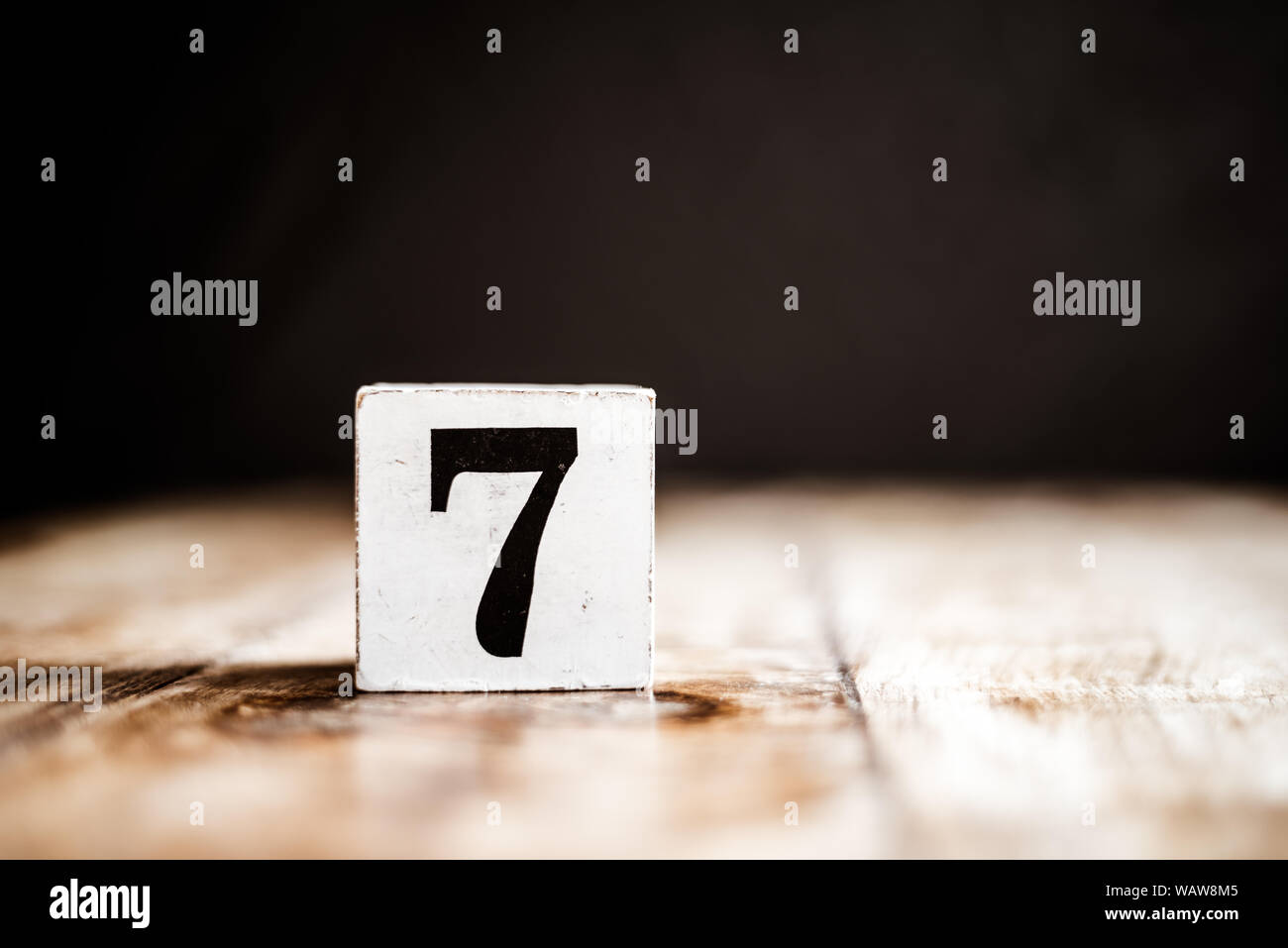 7 - Number 7 - Number Seven - White block with number on wooden table ...