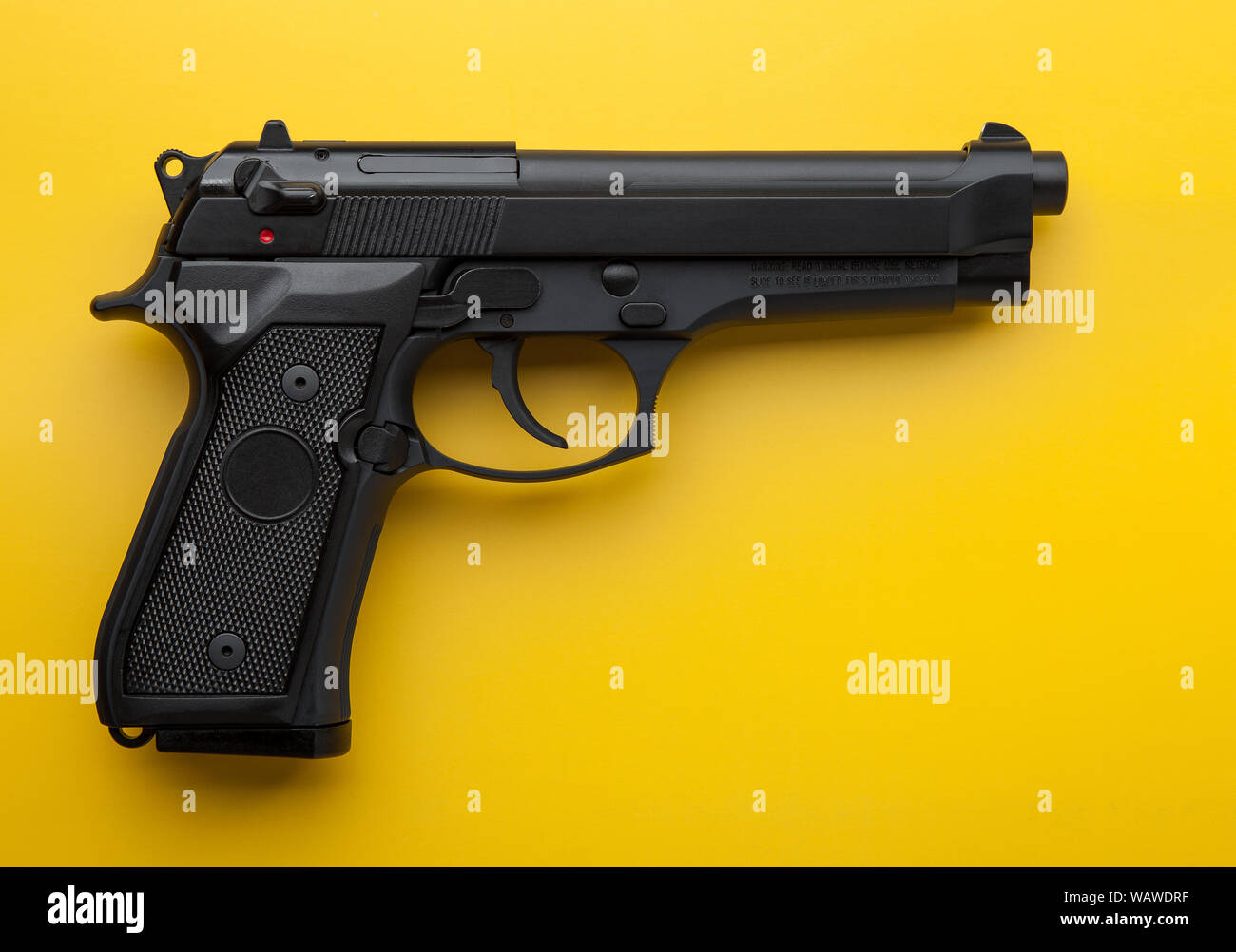 Modern black semi-automatic pistol on a bright yellow background. Short ...