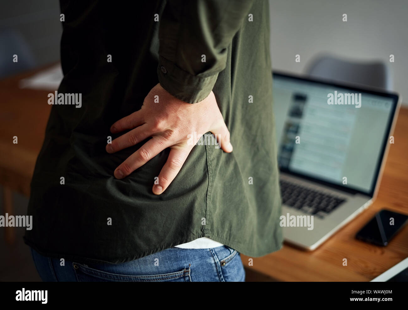 Man suffering from back pain touching his back Stock Photo - Alamy