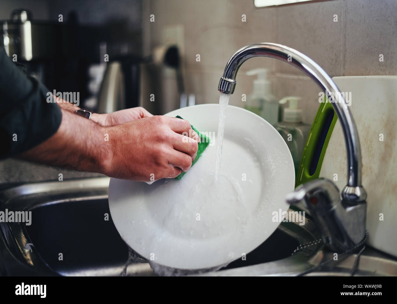Man's hand washing the dish under the kitchen sink faucet Stock Photo ...