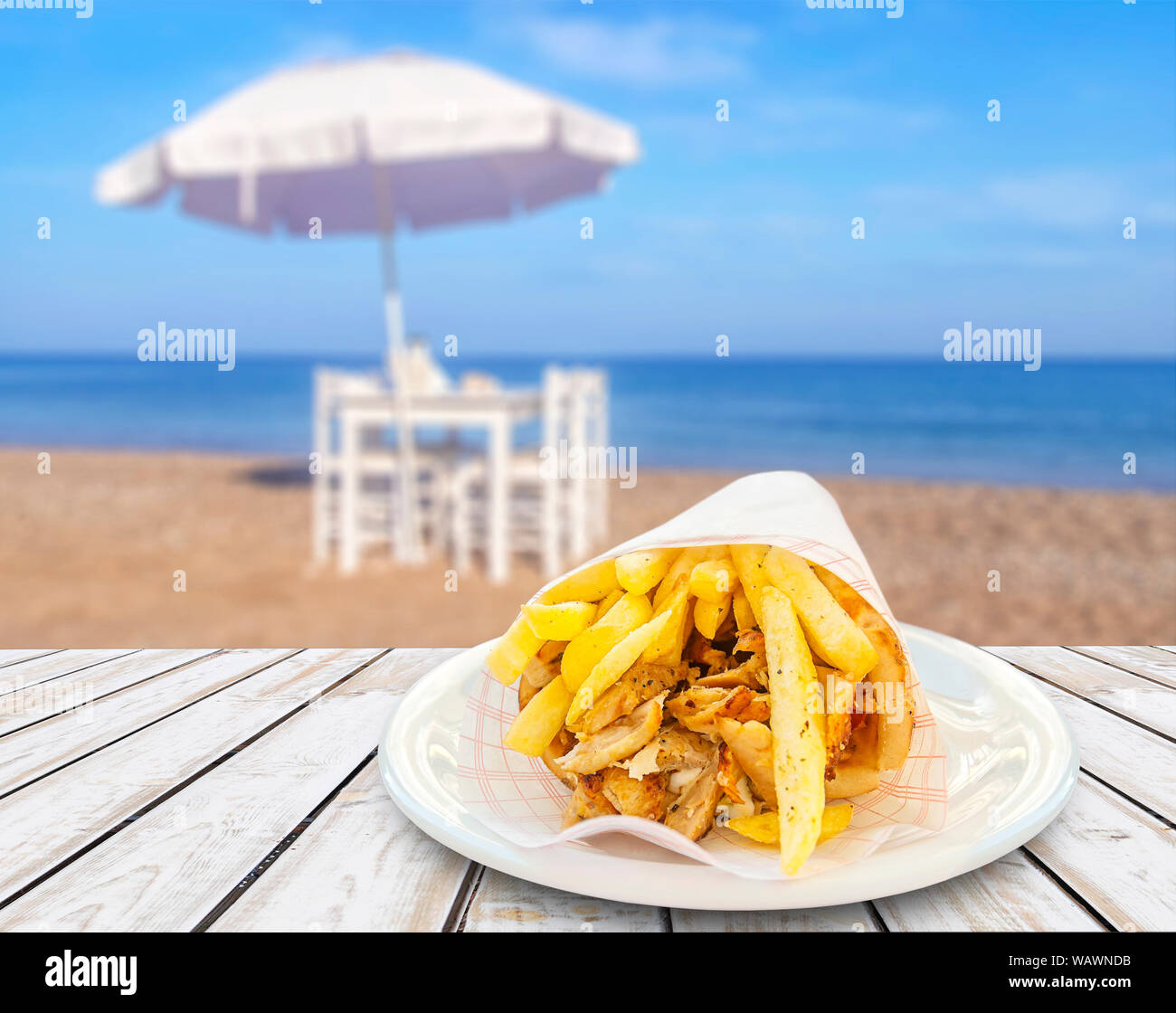 Greek gyro with fries on wooden table in beach background Stock Photo ...