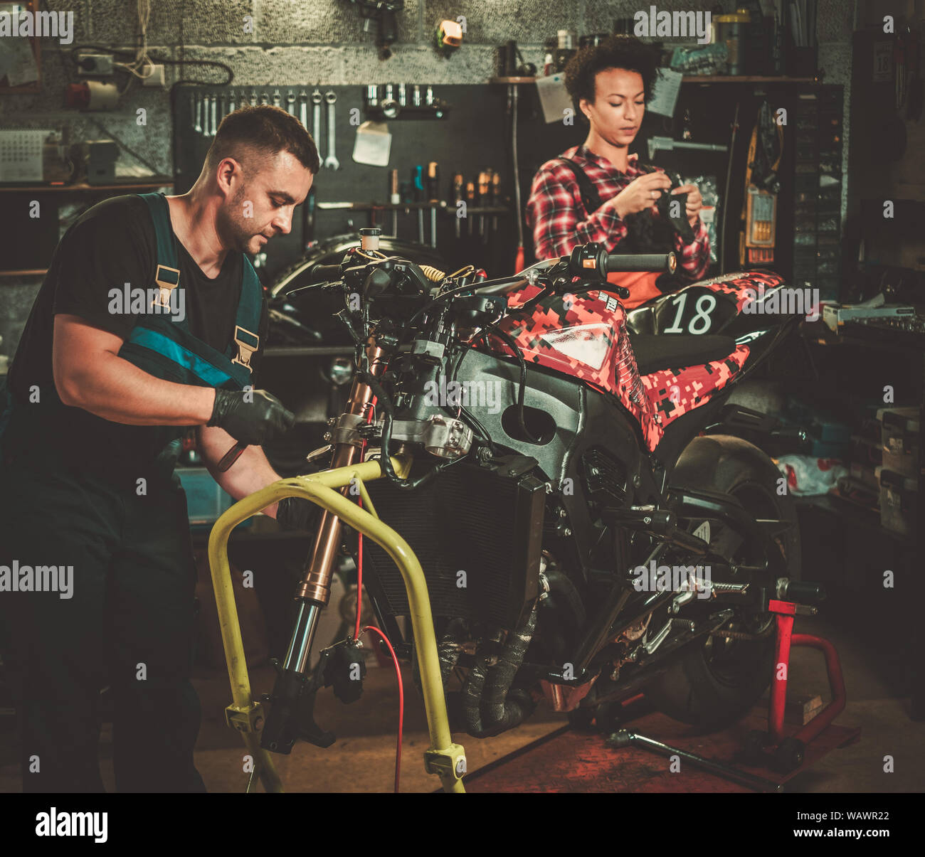 Mechanic and his helper repairing a motorcycle in a workshop Stock ...