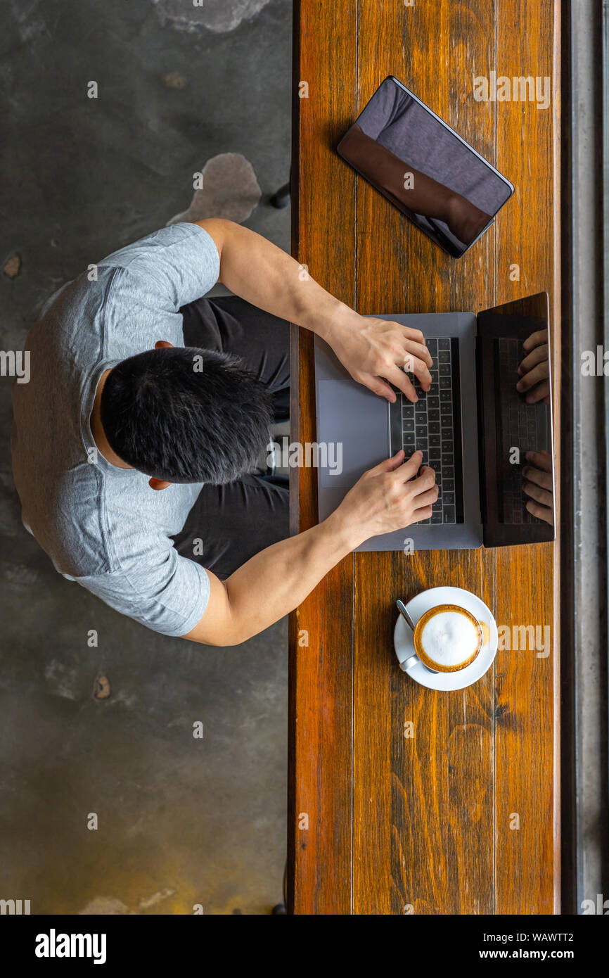 Vertical photo of young Asian man freelancing on laptop Stock Photo - Alamy