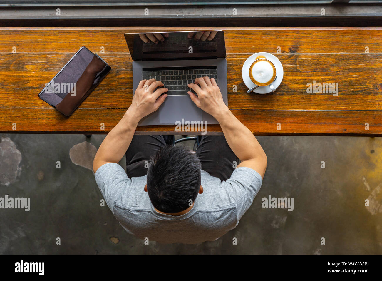 Asian freelancer typing laptop keyboard next to tablet at coffeeshop ...
