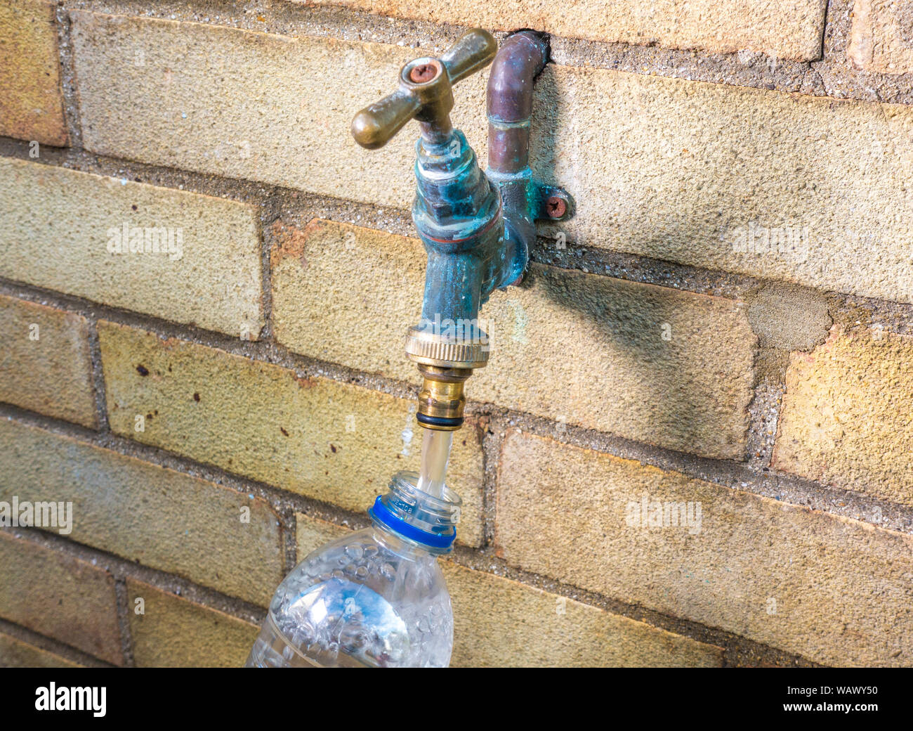 Close POV shot of a small, clear plastic bottle being filled with fresh ...