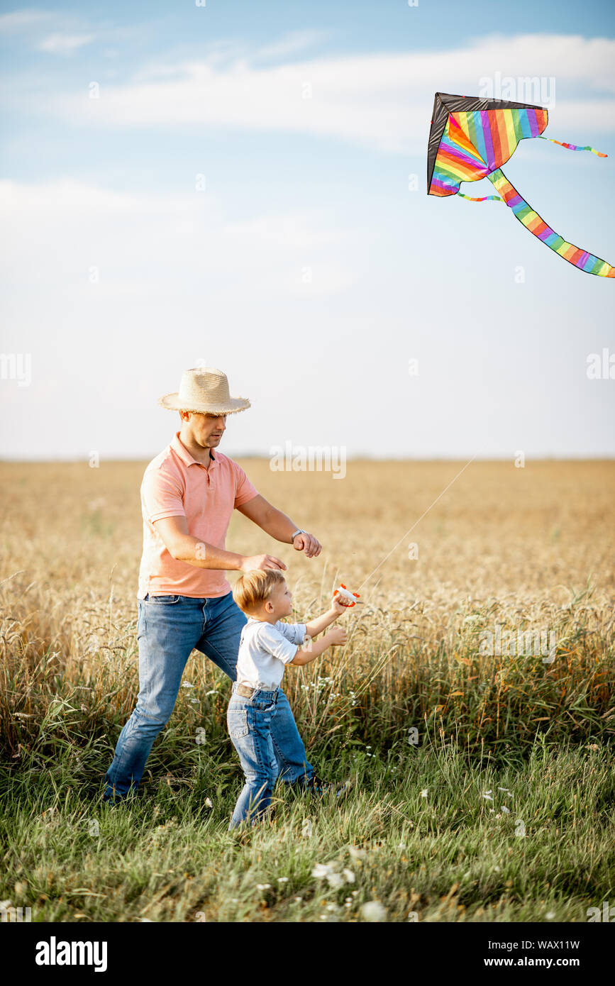 Father with son launching colorful air kite on the field during the ...