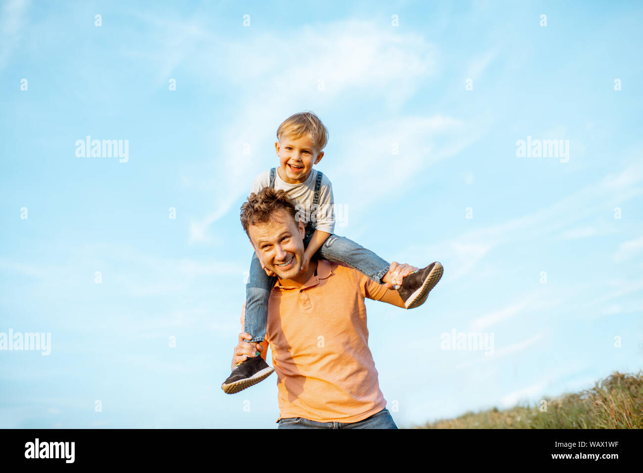 Portrait of a happy father with young son riding on the shoulders on ...