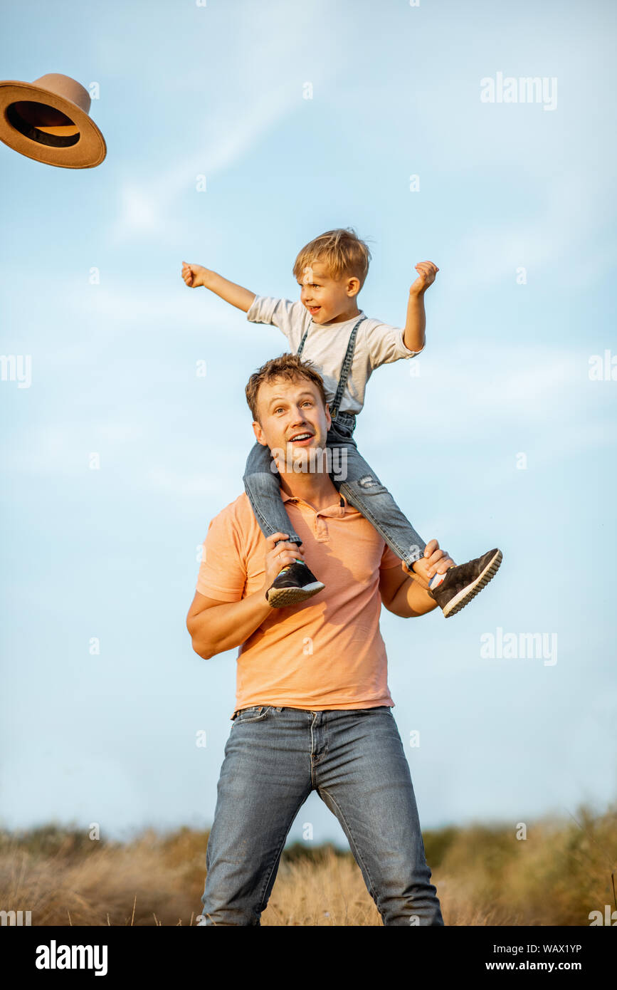 Portrait of a happy father with young son riding on the shoulders on ...