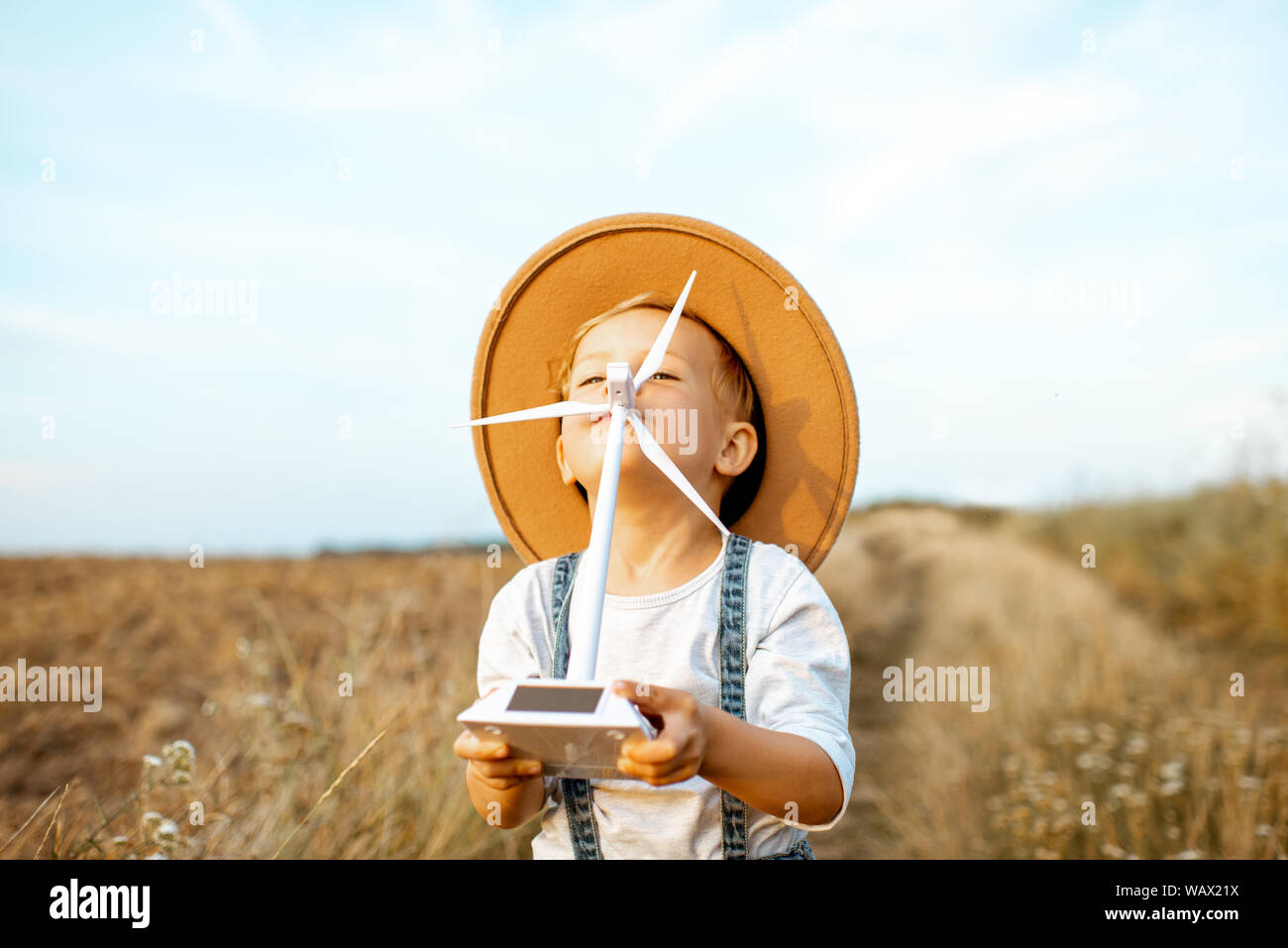 Portrait of a curious young boy playing with toy wind turbine in the ...
