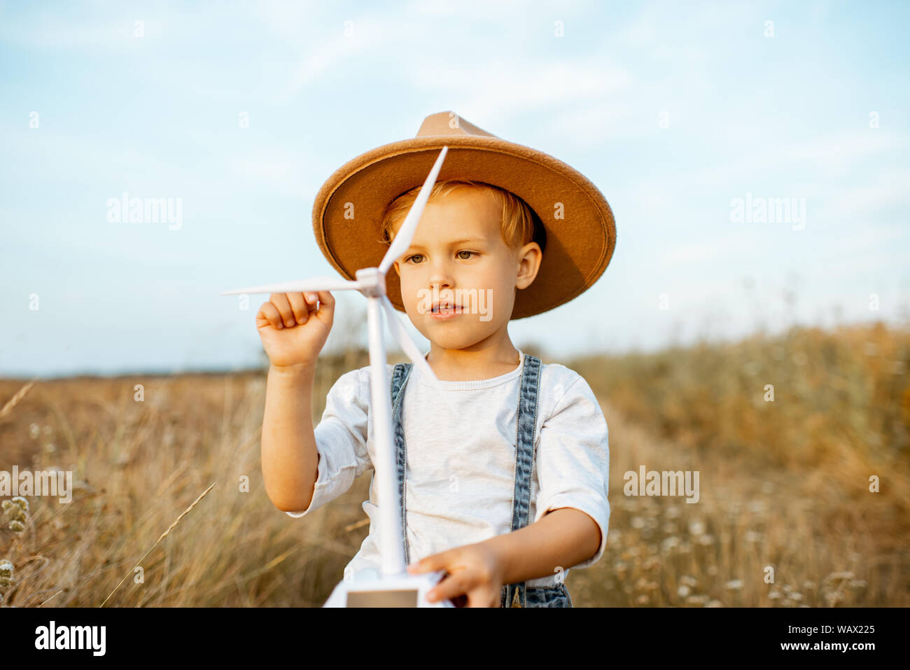 Portrait of a curious young boy playing with toy wind turbine in the ...