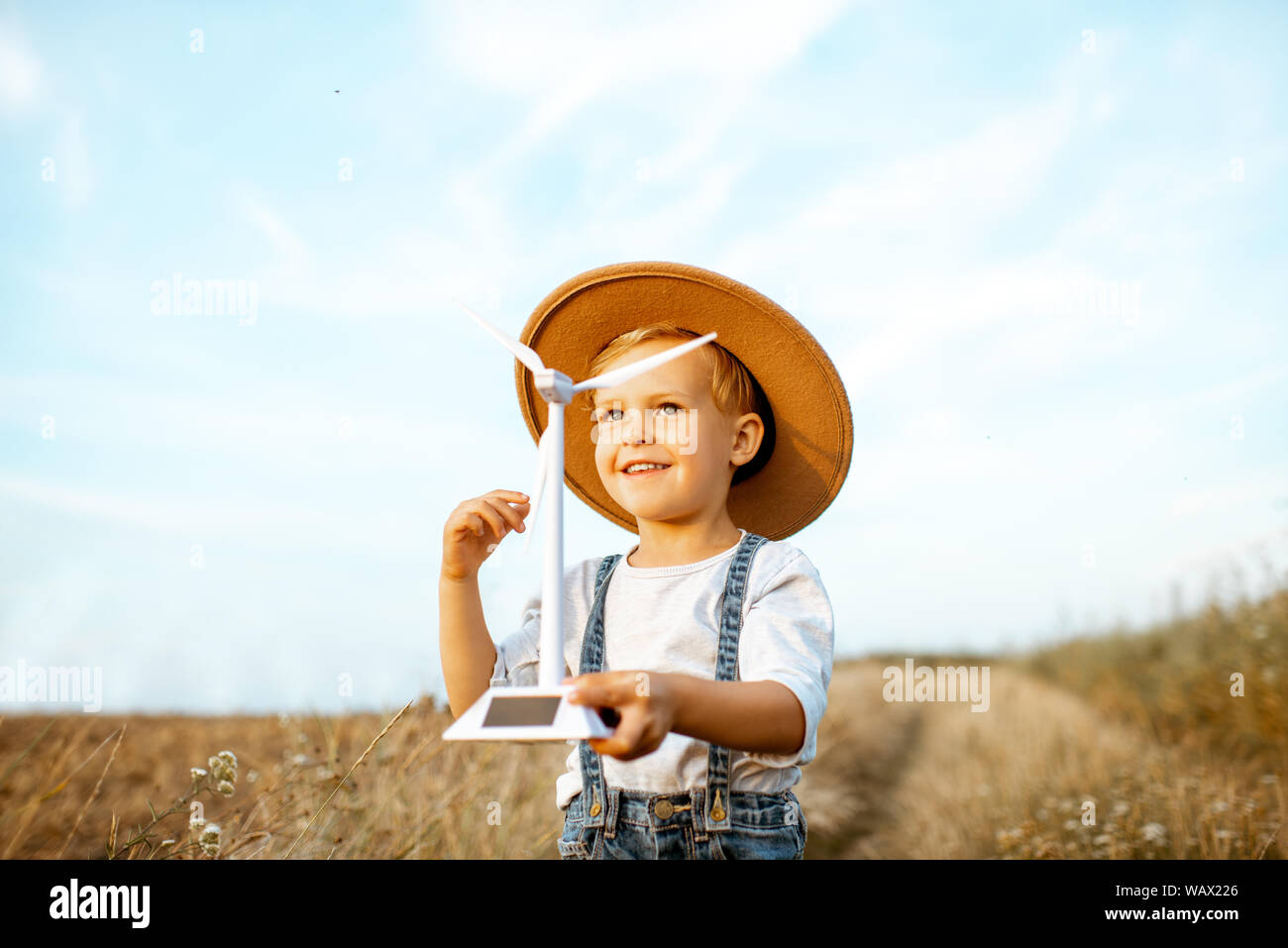Portrait of a curious young boy playing with toy wind turbine in the ...