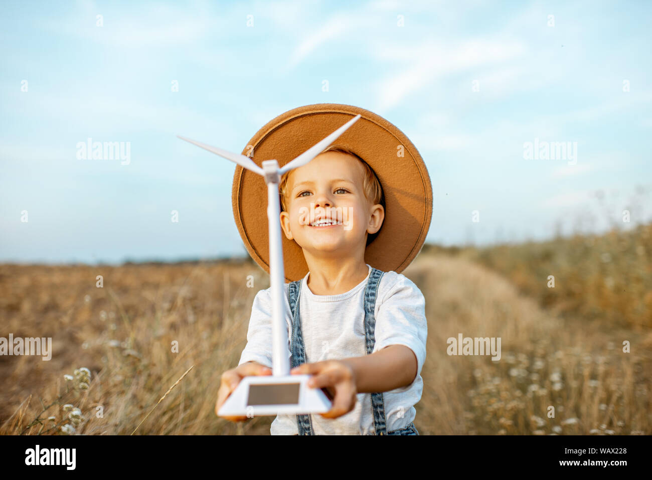 Portrait of a curious young boy playing with toy wind turbine in the ...