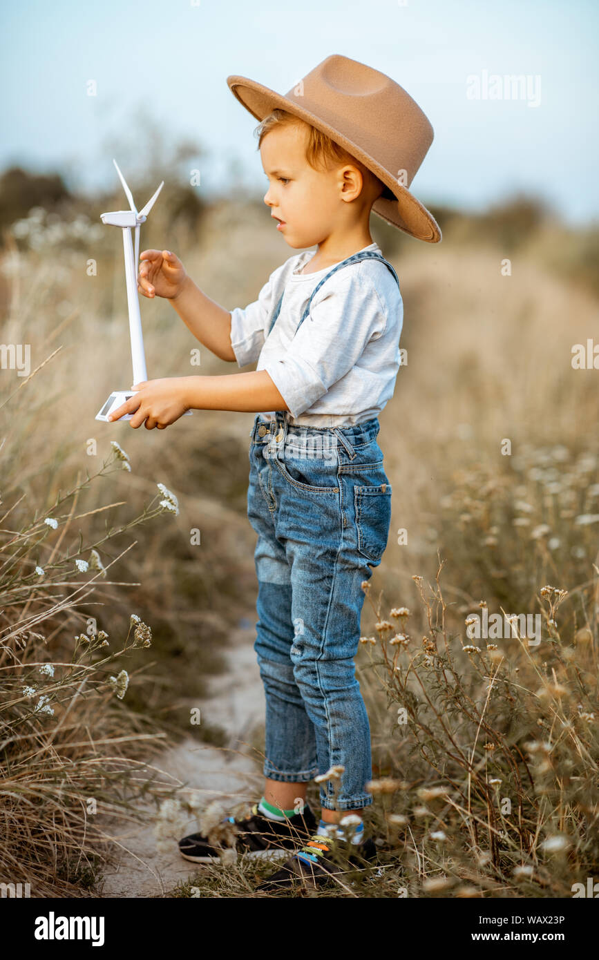 Full body portrait of a curious young boy playing with toy wind turbine ...