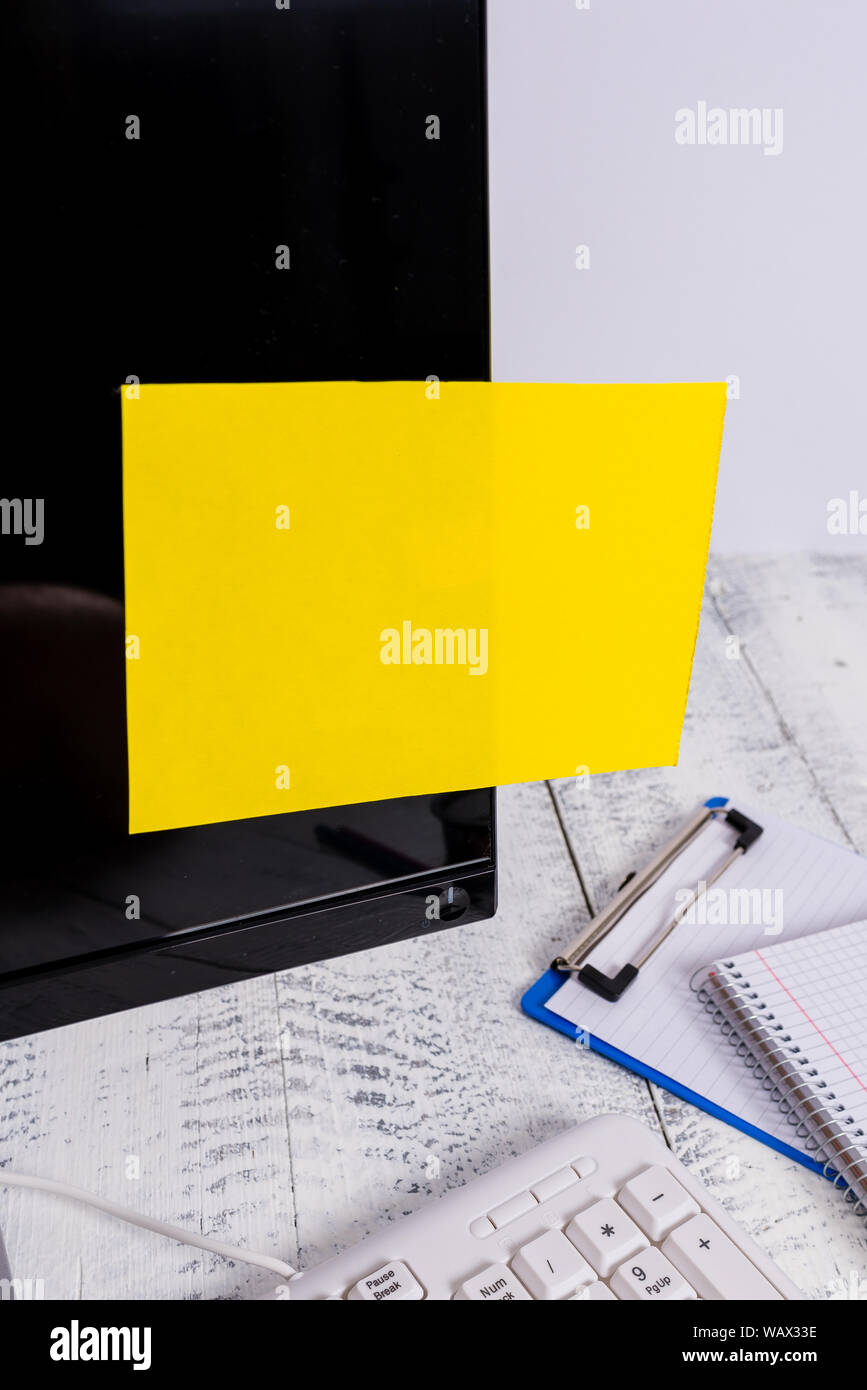 Note paper taped to black computer screen near keyboard and stationary ...