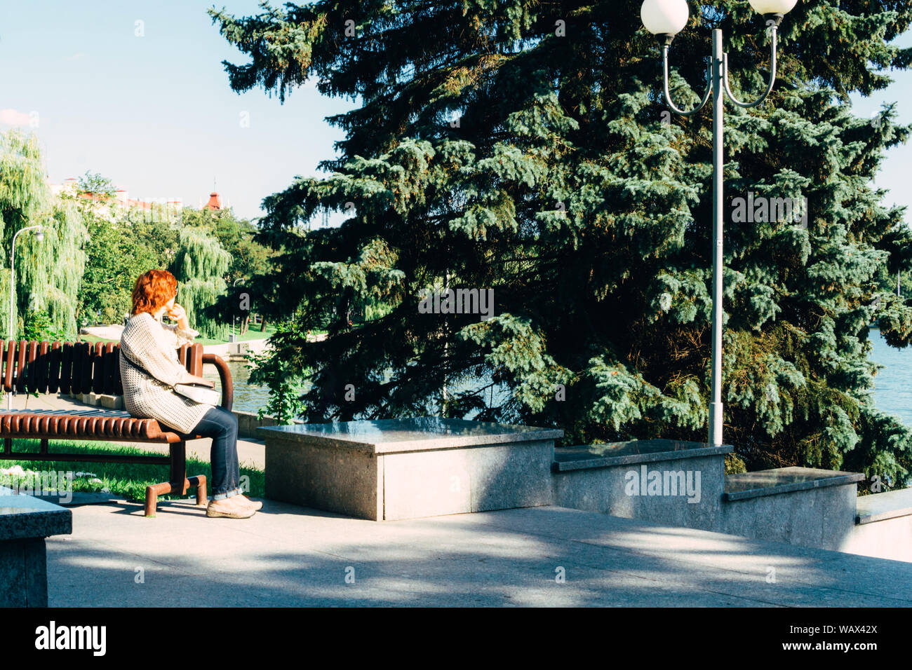 A ginger woman having a rest in park. City landscape with a view of the ...