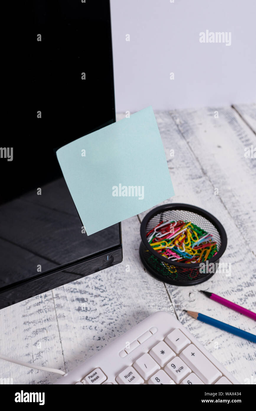 Note paper taped to black computer screen near keyboard and stationary ...