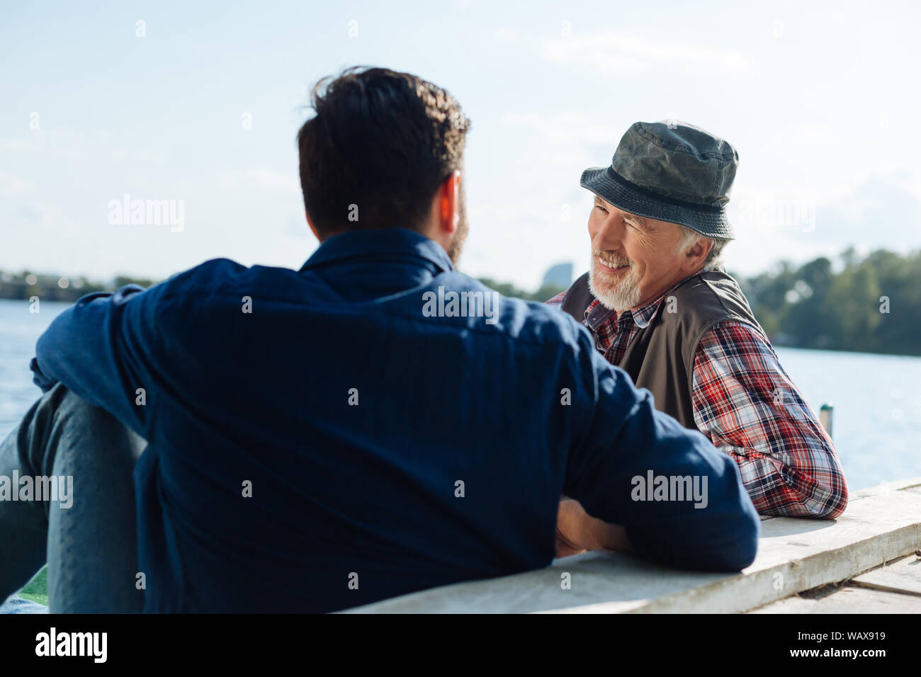 Handsome retired man smiling while talking to son Stock Photo - Alamy