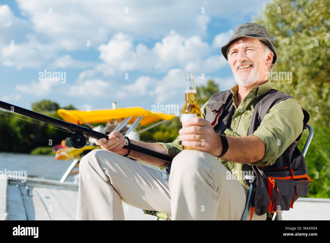 Man smiling while fishing and drinking beer Stock Photo - Alamy