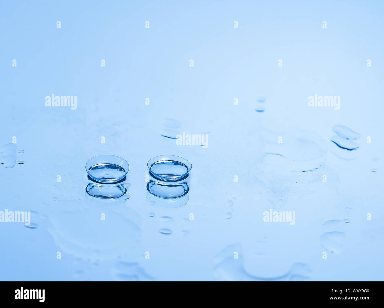 Contact lenses for the eyes on the glass among the drops of water in ...