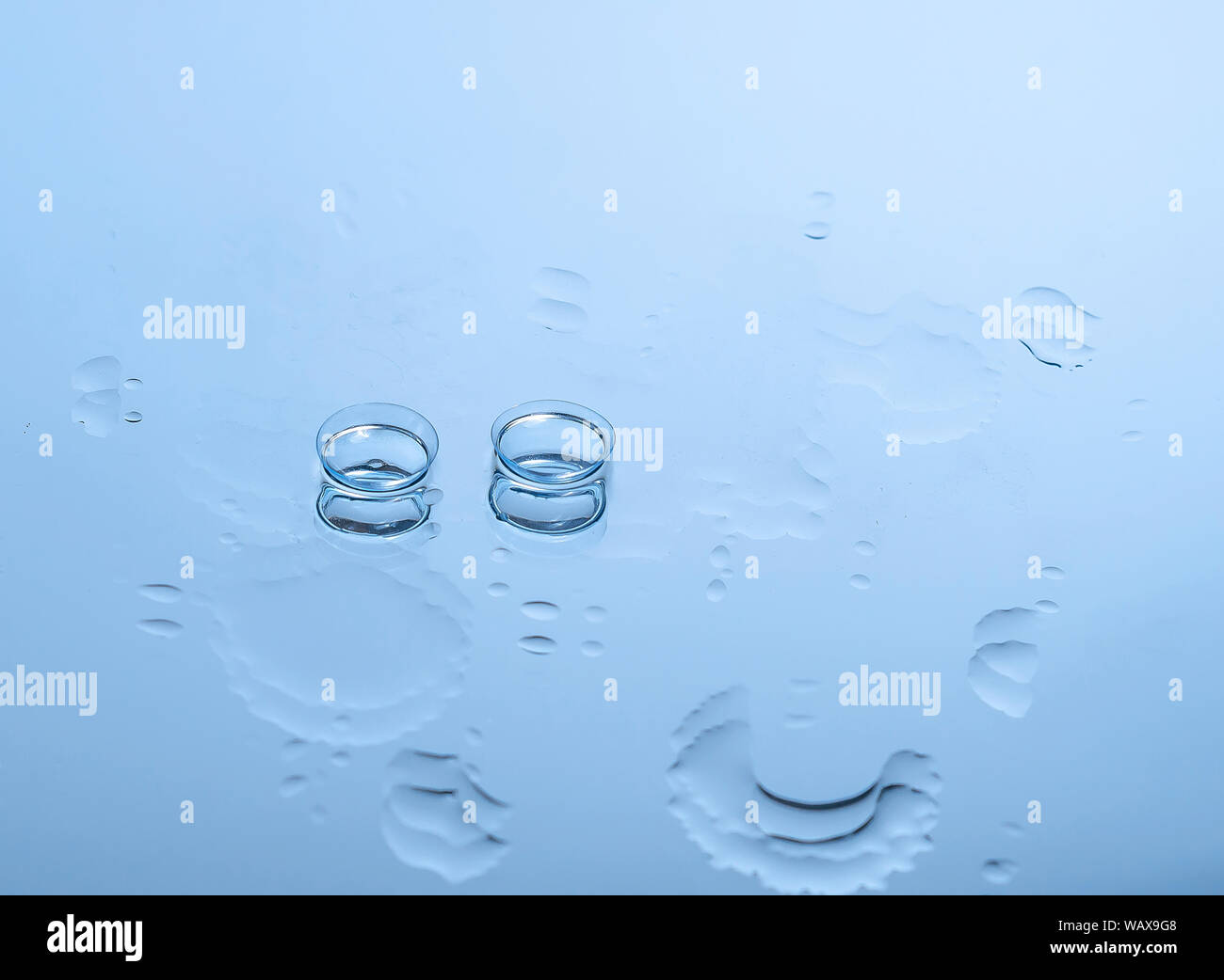 Contact lenses for the eyes on the glass among the drops of water in ...