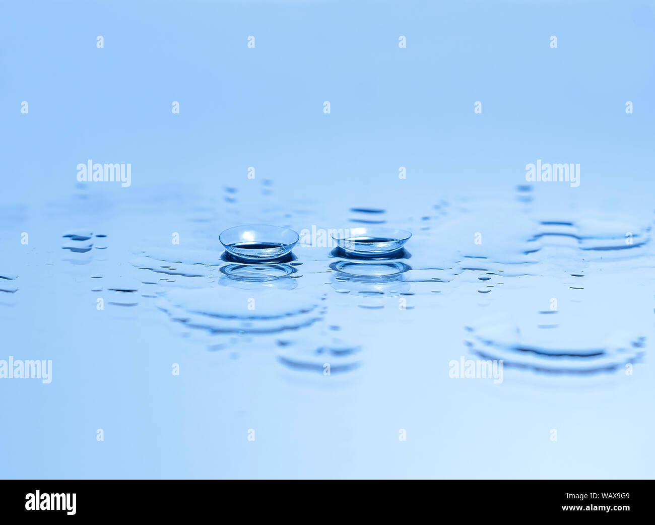 Contact lenses for the eyes on the glass among the drops of water in ...