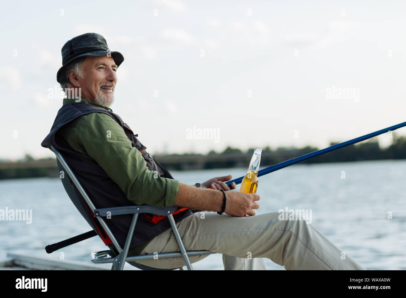 Man smiling while enjoying evening fishing and drinking beer Stock ...