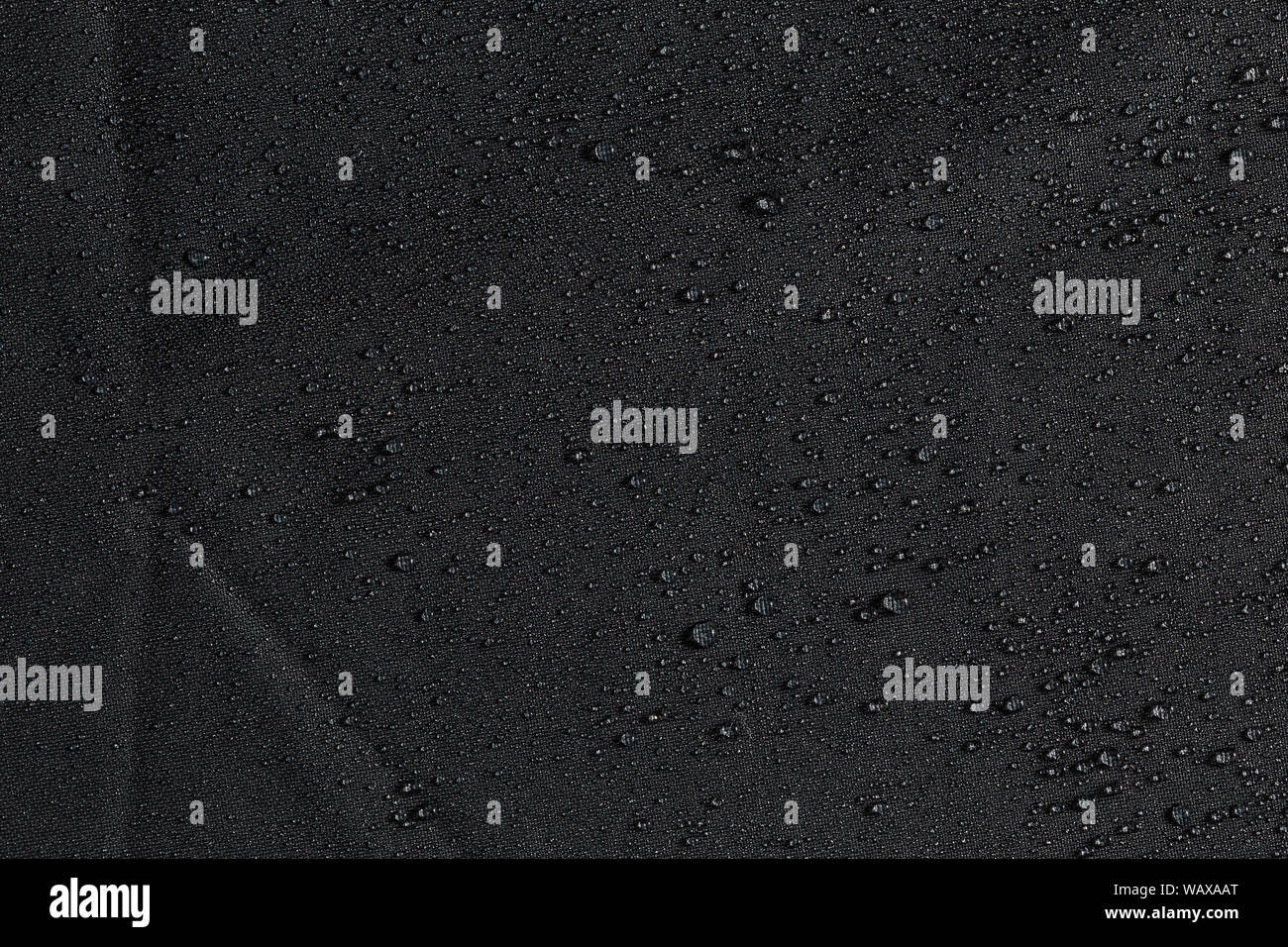 dark gray waterproof hydrophobic flat cloth closeup with rain drops ...