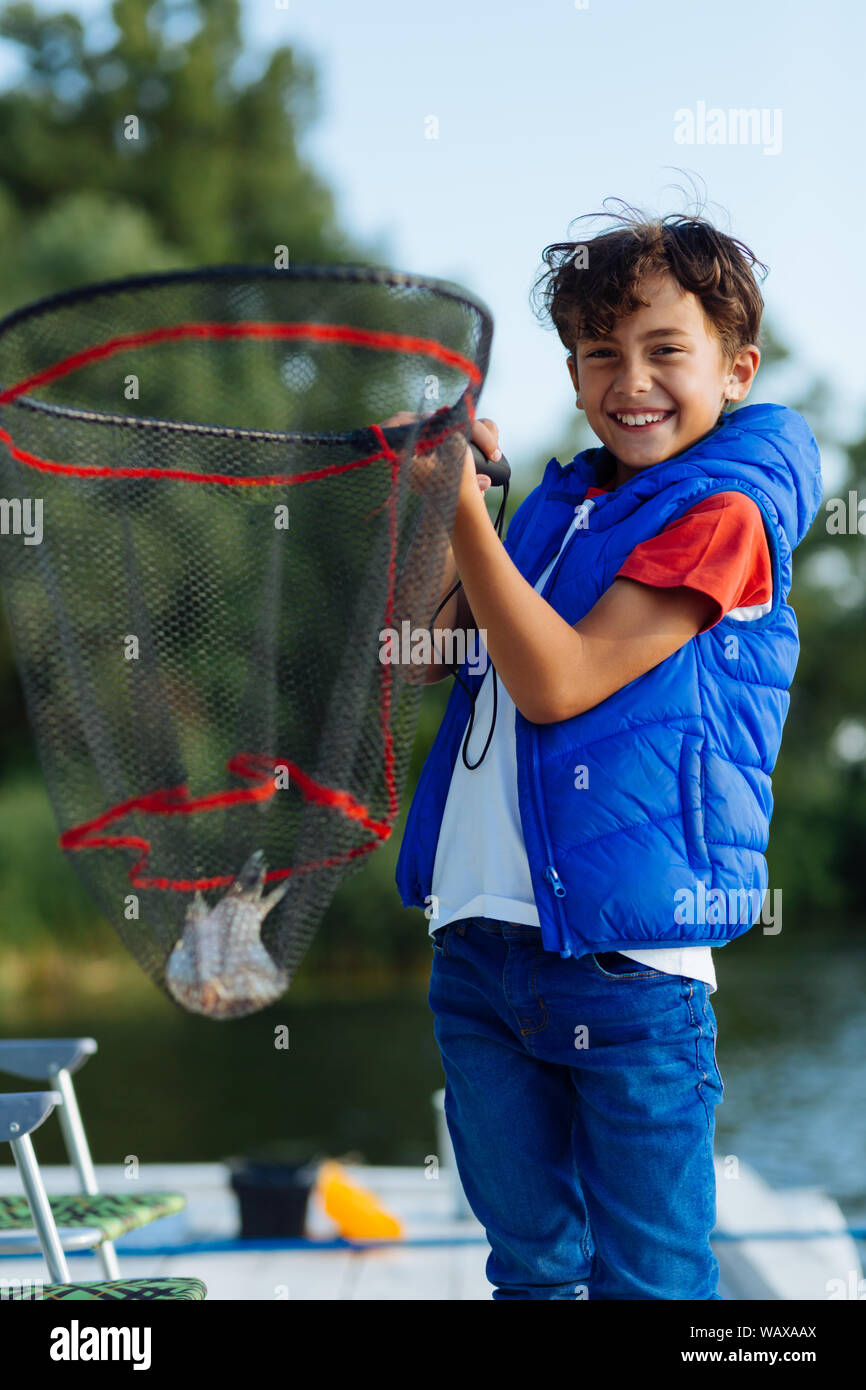 Happy beaming boy holding fishing net with little fish Stock Photo - Alamy