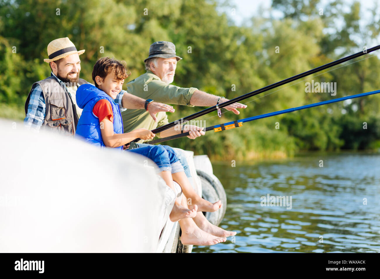 Boy feeling happy while fishing with father and grandfather Stock Photo ...