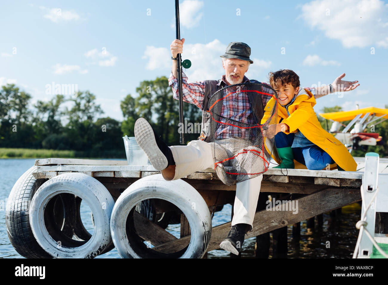 Boy after catching fish into net with grandfather Stock Photo - Alamy