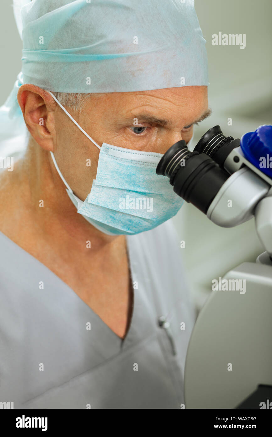 Serious focused man looking into the microscope lenses Stock Photo - Alamy
