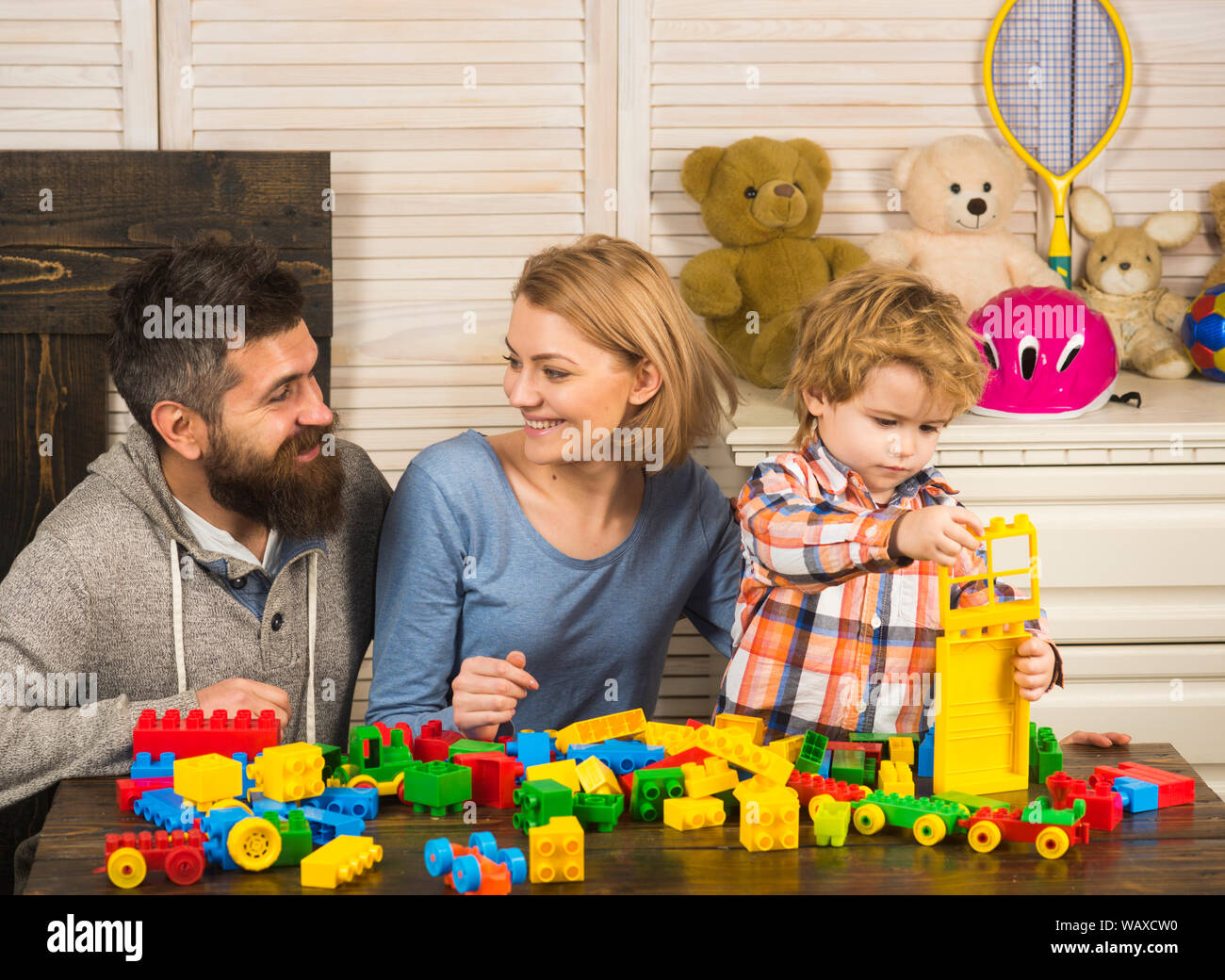 Parents with happy faces and kid makes brick constructions. Father ...