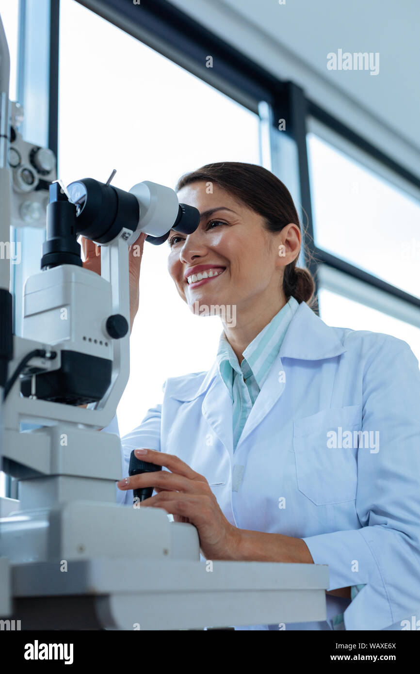 Cheerful female doctor looking into the microscope Stock Photo - Alamy