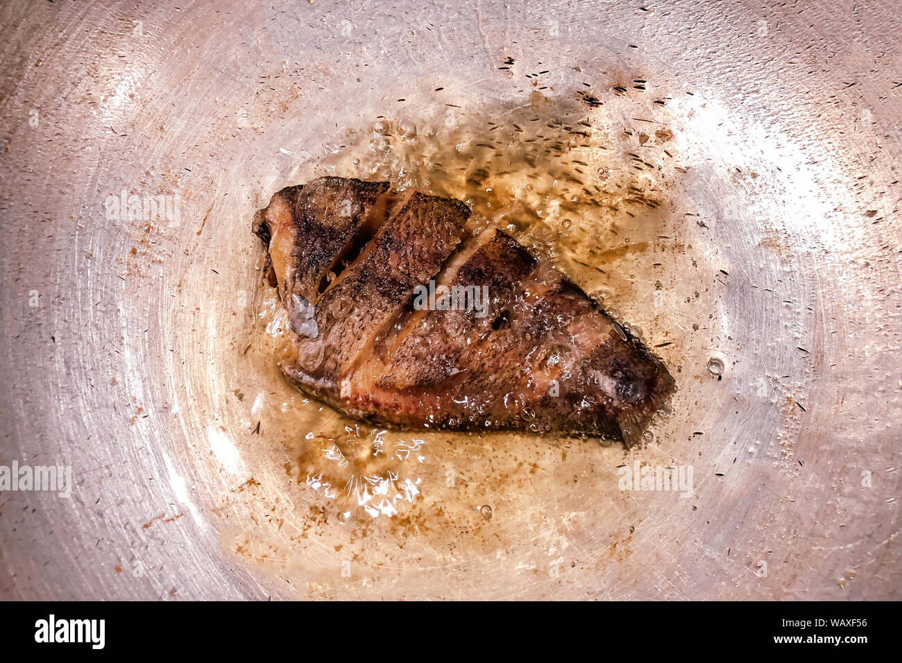 Asian style Tilapia fish fried in frying pan with very hot oil top view ...